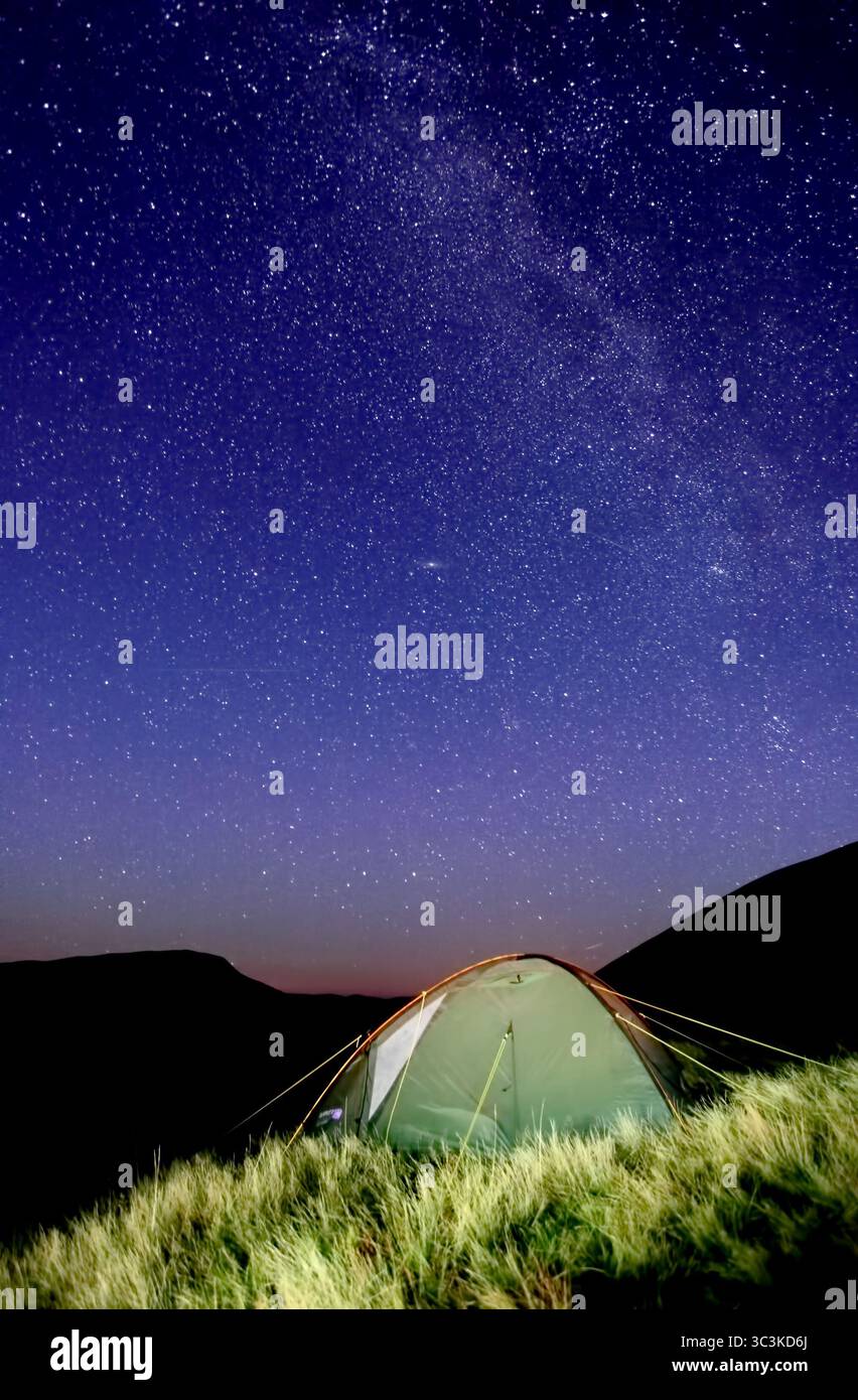 tent at night in a wild mountain scenery and the sky full of stars ...