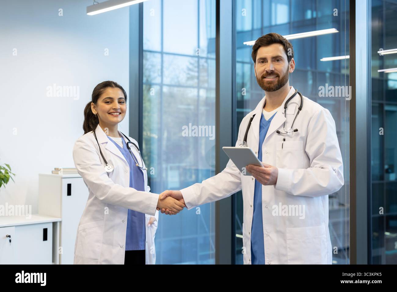 Two doctors shake hands, smiling. The photo depicts a collaboration in ...