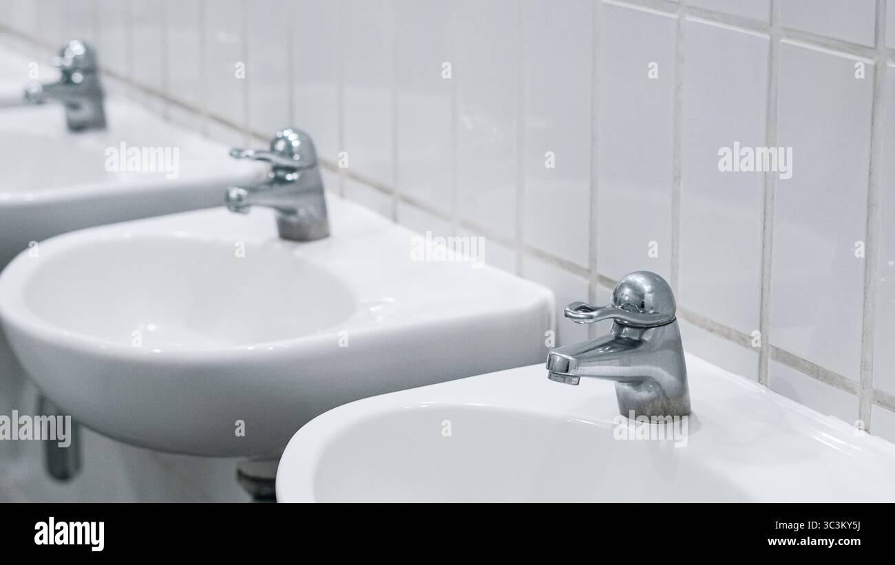 Hygienic white restroom interior with multiple sinks for hand washing ...