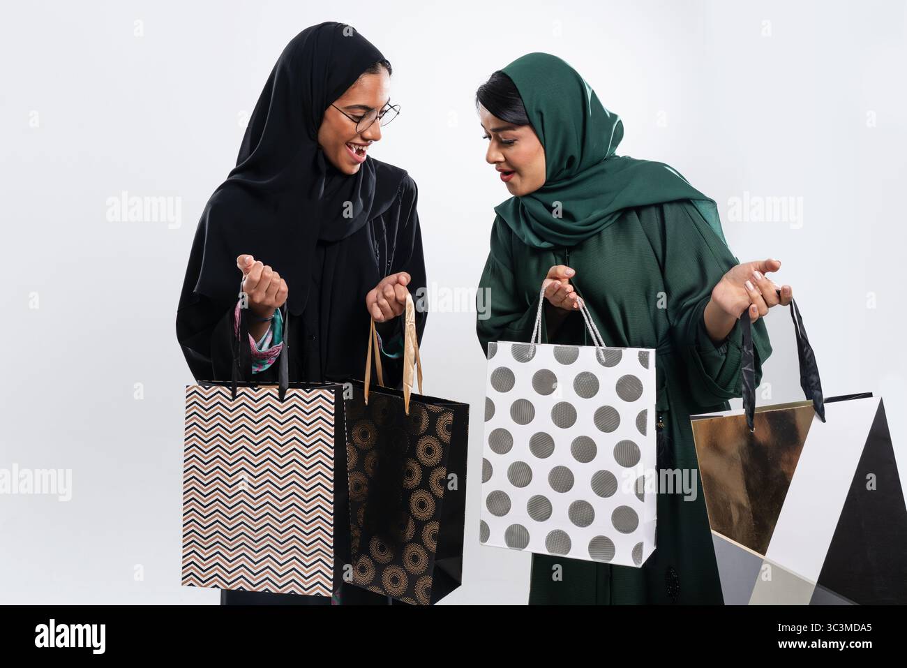 Two smiling arab female friends wearing traditional abayas are showing ...