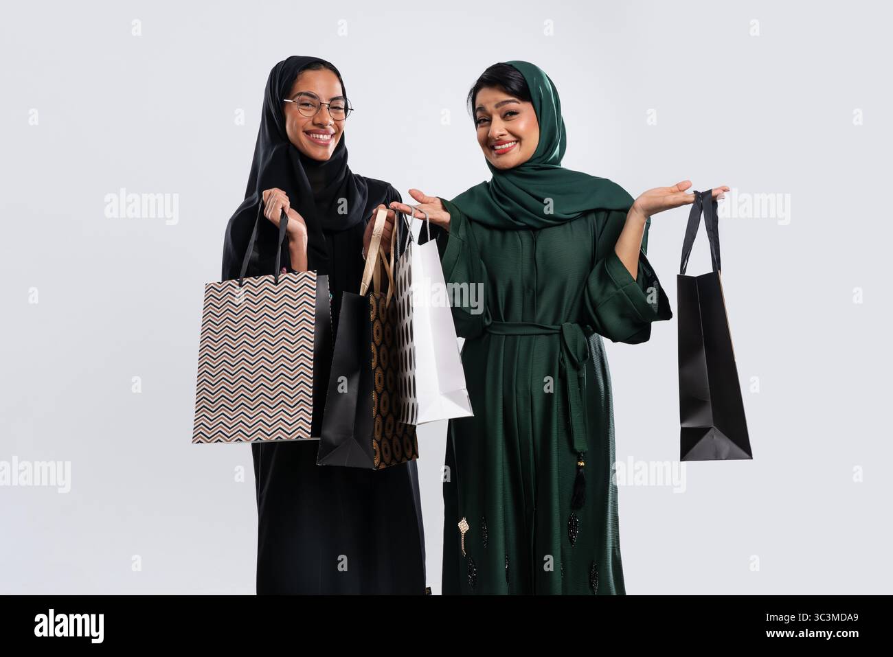 Two happy emirati women wearing traditional abayas are showing their ...
