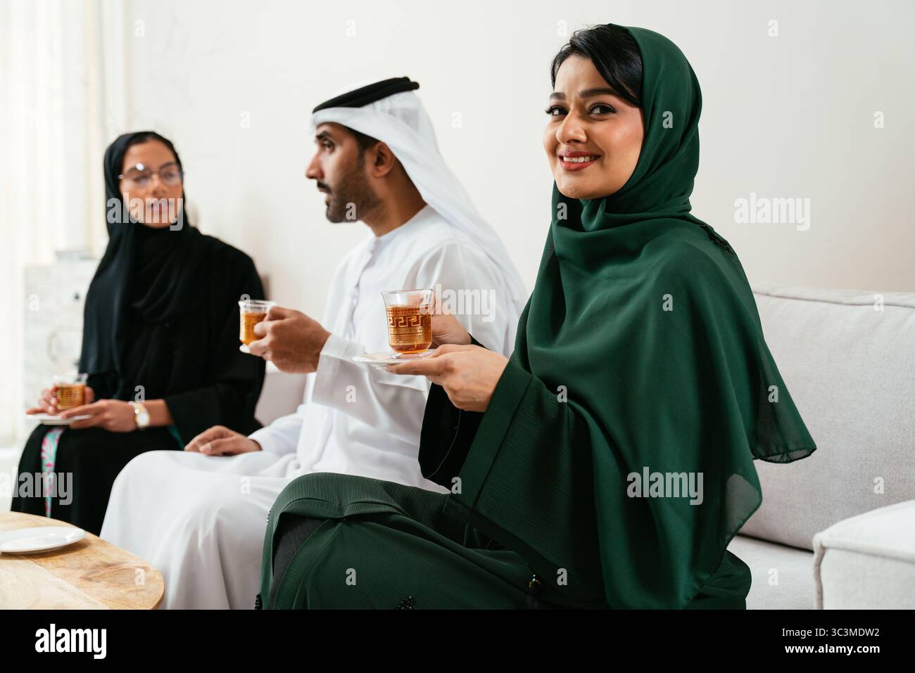 Emirati men and women in traditional abayas and kanduras sit on a ...