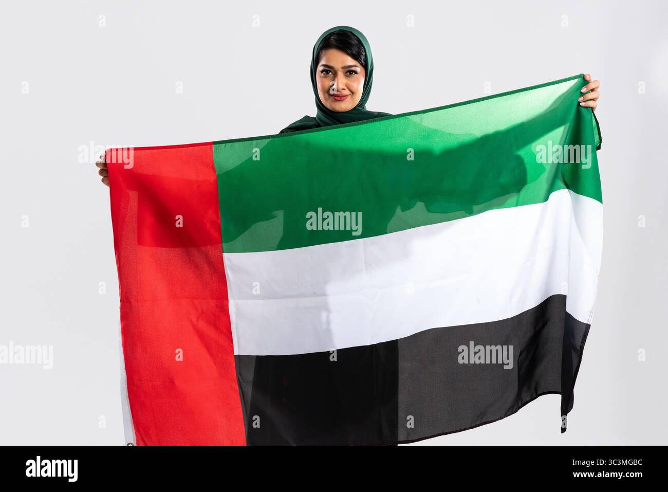 Emirati woman wearing a hijab proudly holds the national flag of the ...