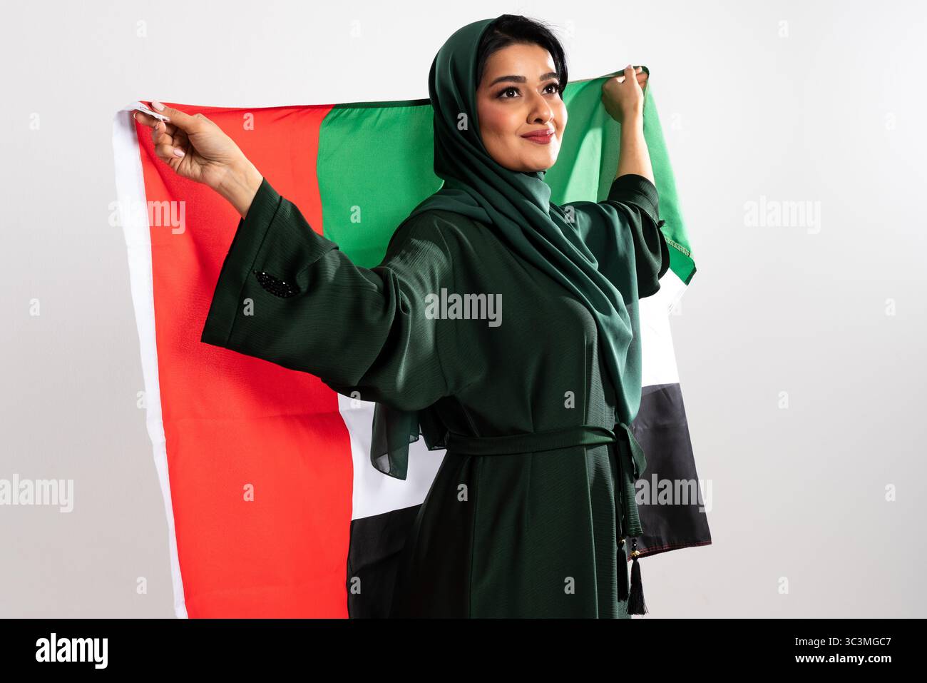 Emirati woman wearing a traditional green abaya and hijab proudly holds ...