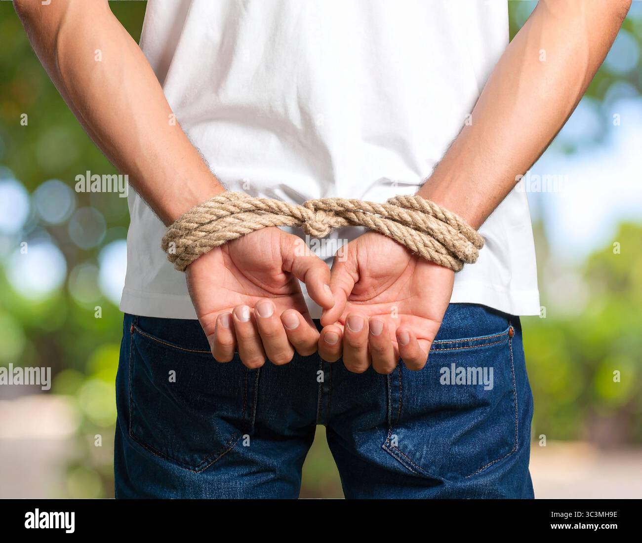 "White man standing with hands tied behind his back with rope ...