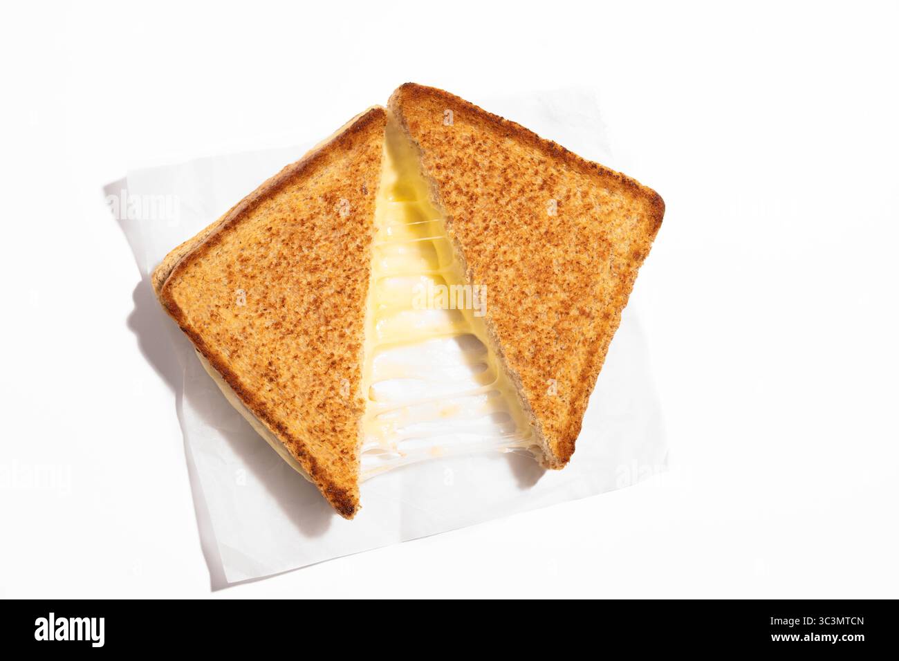 A delicious grilled cheese sandwich sits on white parchment paper over ...