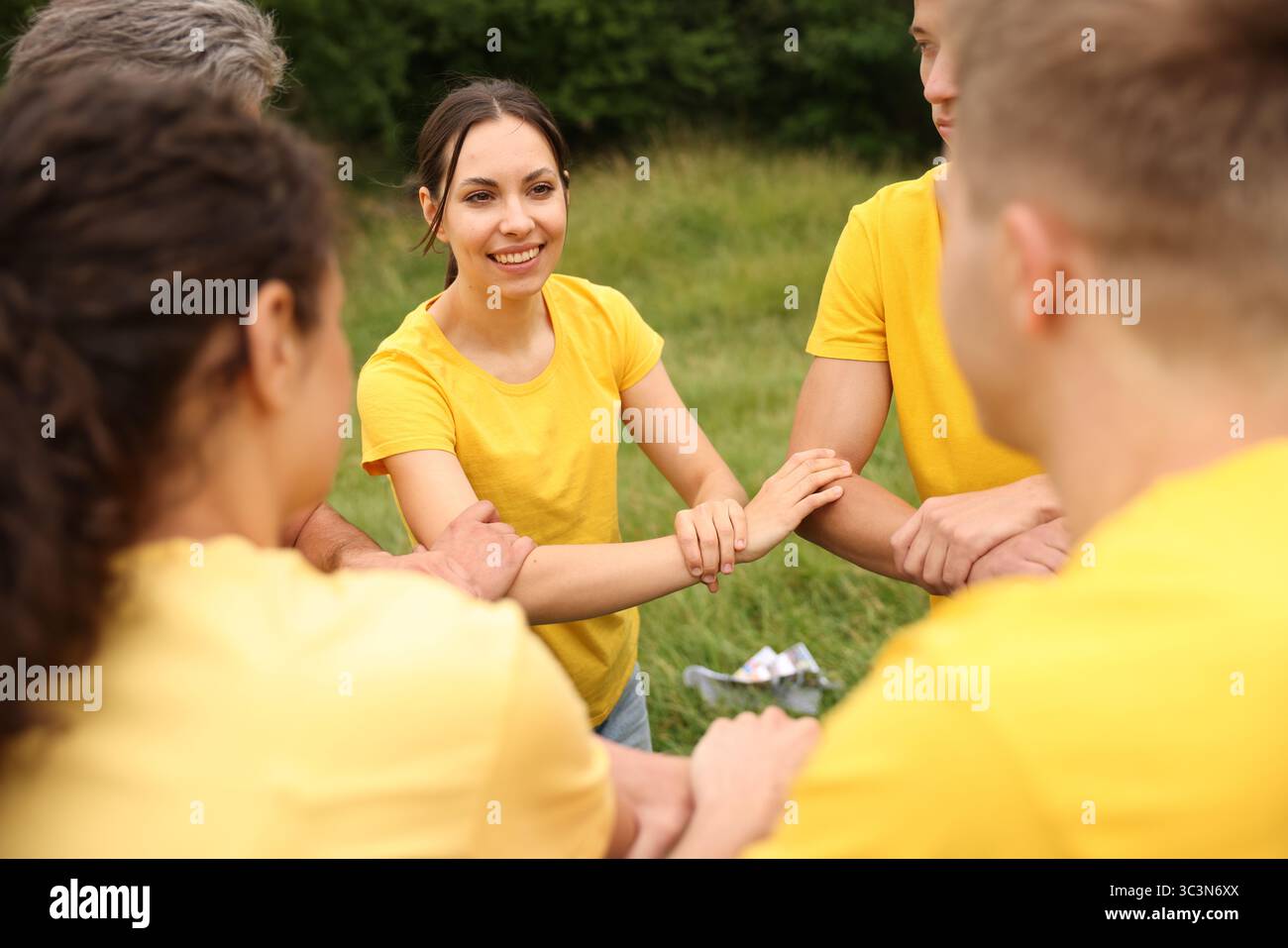 Team building. Group of happy people joining hands outdoors Stock Photo ...