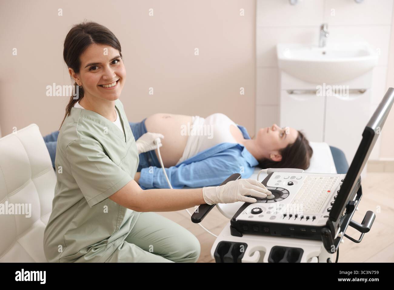 Sonographer conducting woman's prenatal ultrasound examination in ...