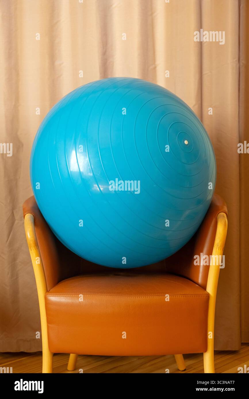 Blue gym ball rests on the armchair in the living room, abstract ...