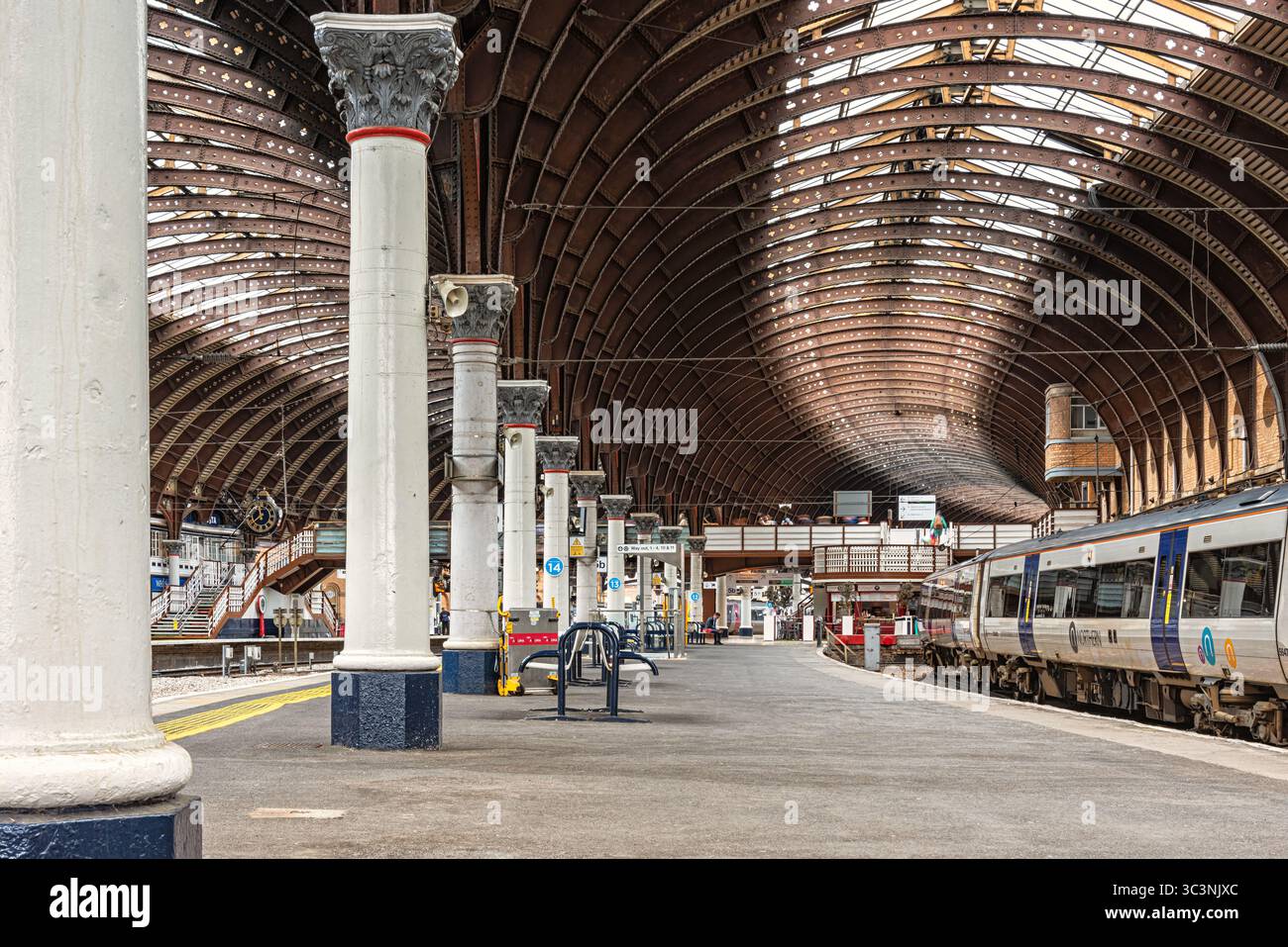 A railway station platform leads to a footbridge with a balcony. There ...