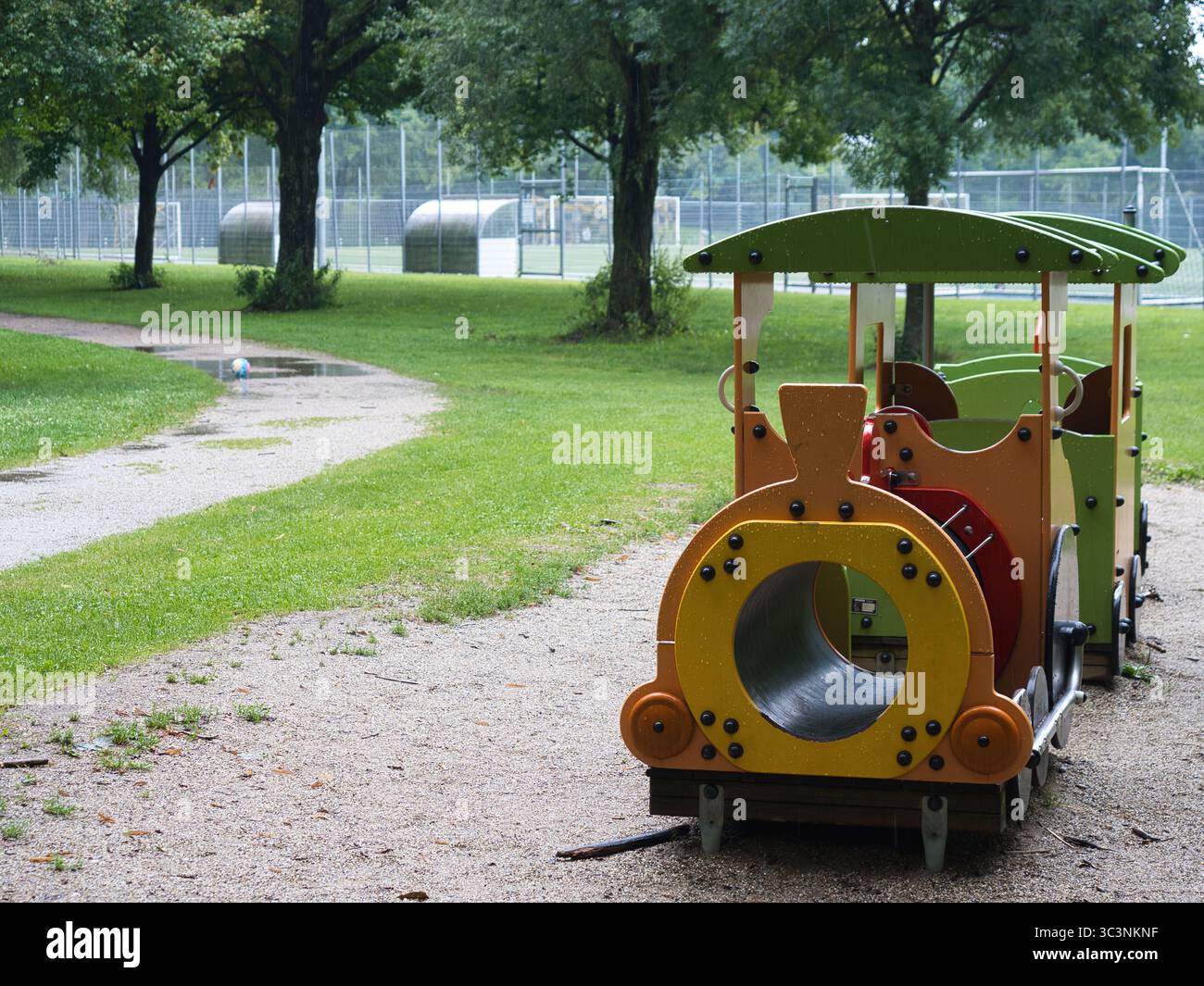 Front view of a colorful wooden playground train on a rainy day. In the ...