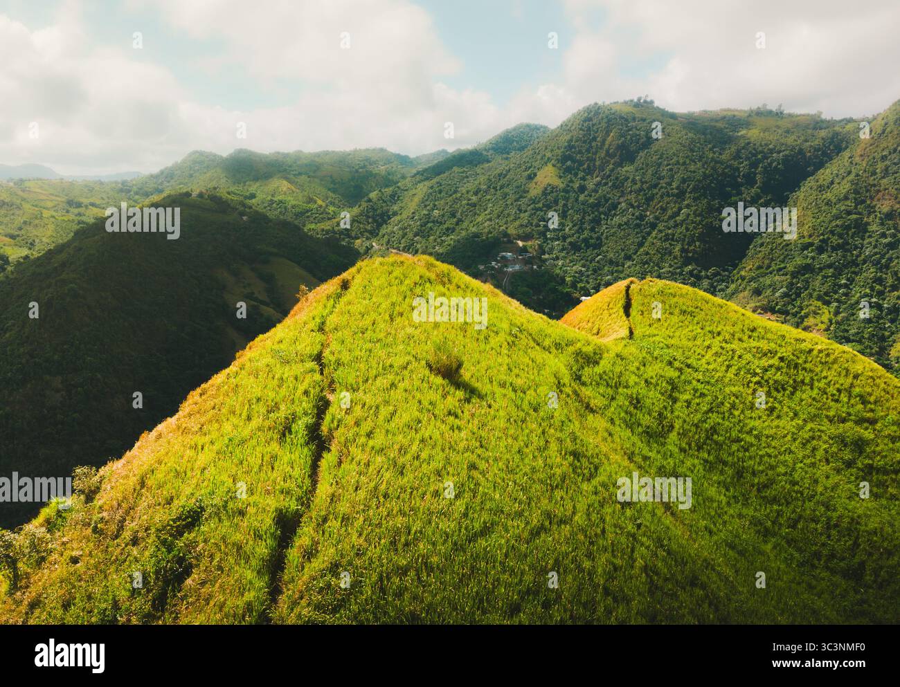 Lush green hills under a cloudy sky, with sunlight highlighting the ...