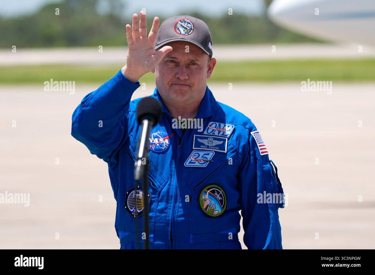 Pilot Mike Fincke, of NASA, waves to media after arriving at the ...