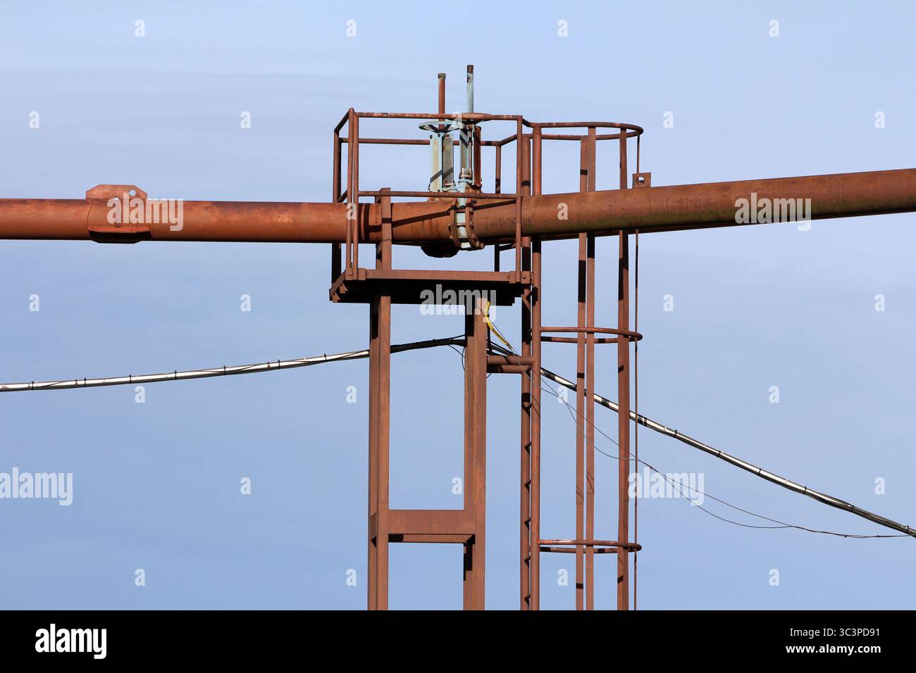 A rusted steel structure supports a large pipeline with an attached ...
