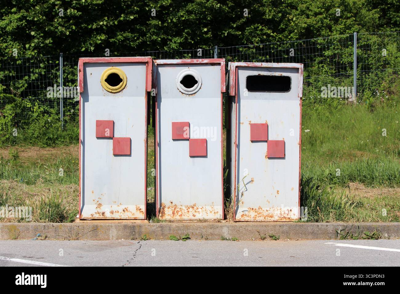 Three rusted metal recycling bins with colored circular and rectangular ...