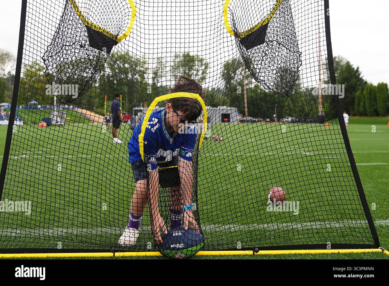 A fan retrieves a ball from a throwing net in a kids' field before the ...