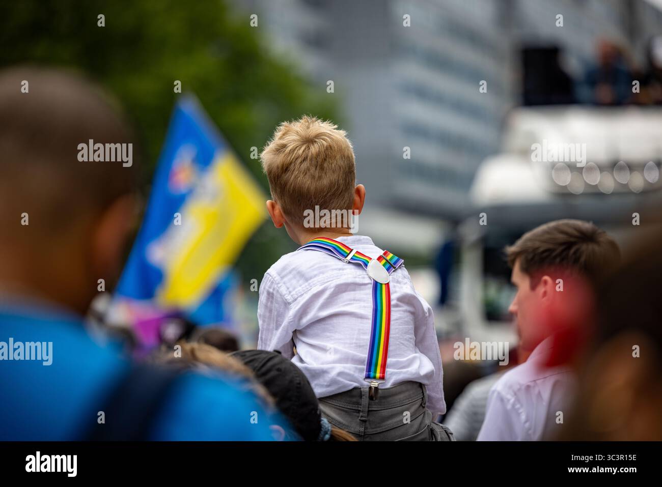 A young child sits atop their parents shoulders and observes the ...