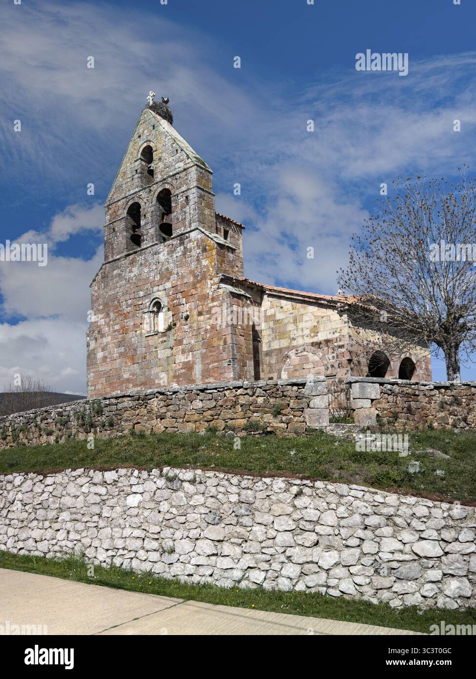Ancient stone church with bell gable and surrounding wall in a rural ...