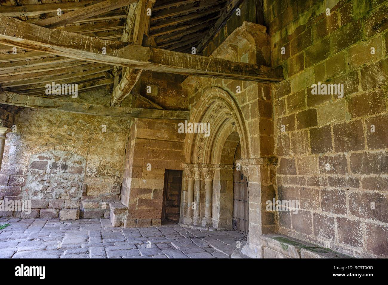 Historic stone arch with detailed carvings framing a wooden church door ...