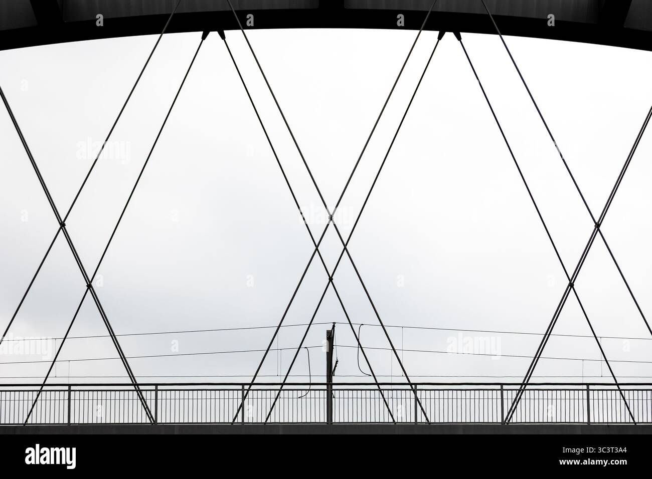 Steel cables supporting a modern pedestrian bridge with a curved arch ...