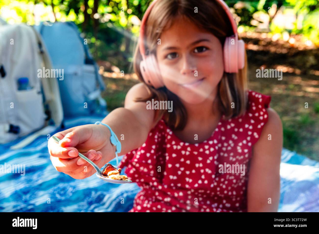 Girl sharing cereal outdoors wearing headphones and backpack Stock ...