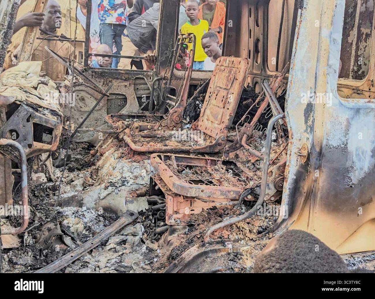 People gather around the charred remains of a burned vehicle following ...