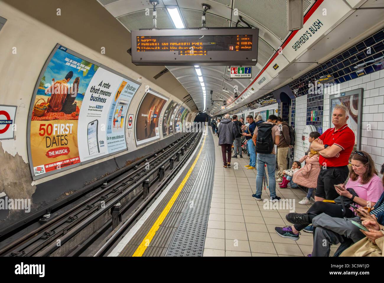 Passengers wait for a train on the platform at Shepherd's Bush London ...