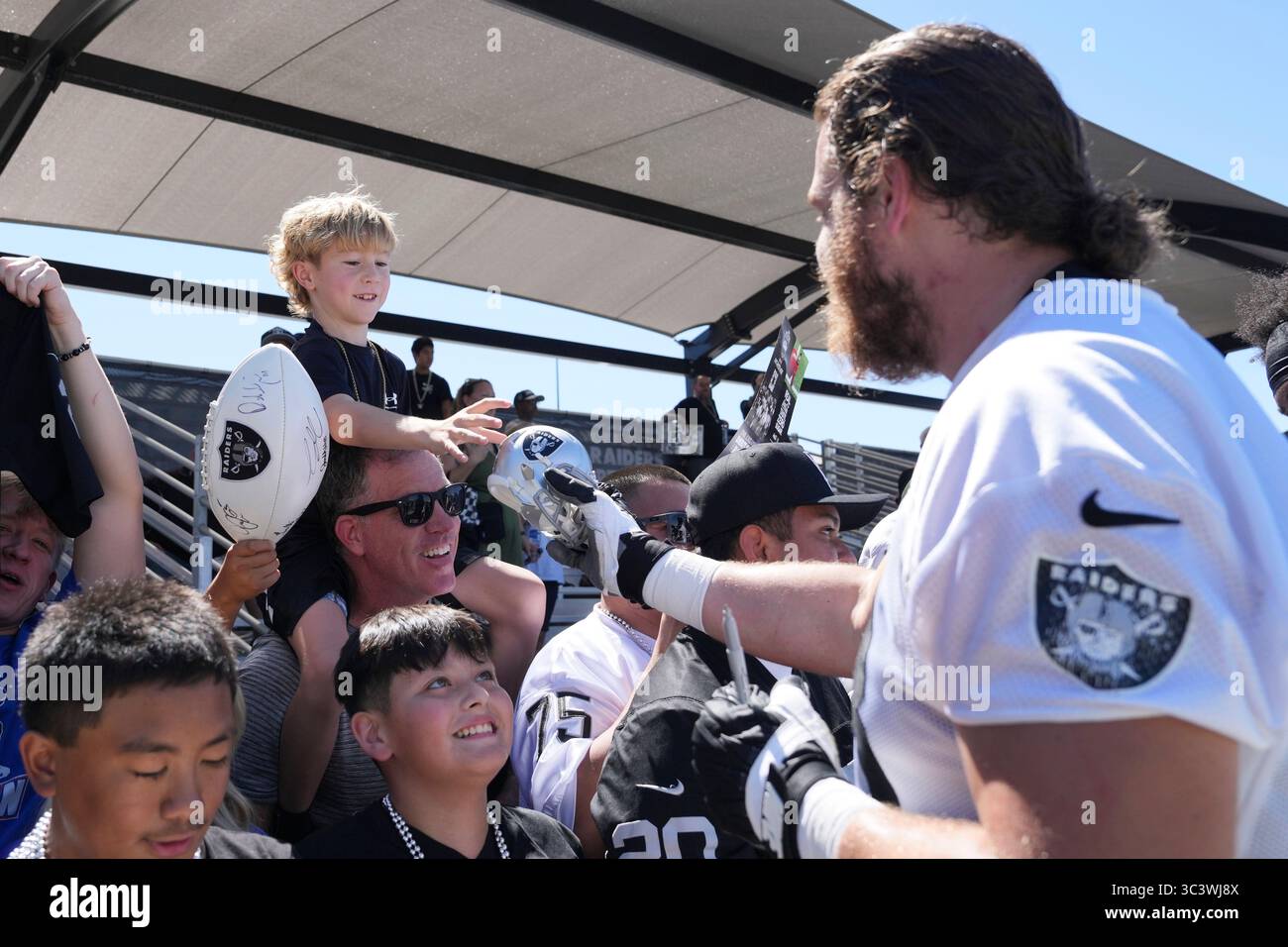 Las Vegas Raiders guard Jackson Powers-Johnson, right, gives autographs ...
