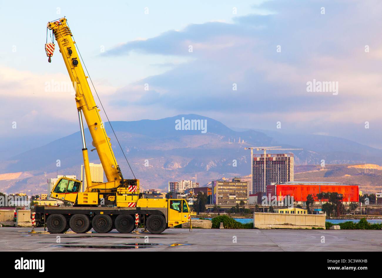 A yellow wheeled truck crane stands in the port of Izmir Turkey. Heavy ...