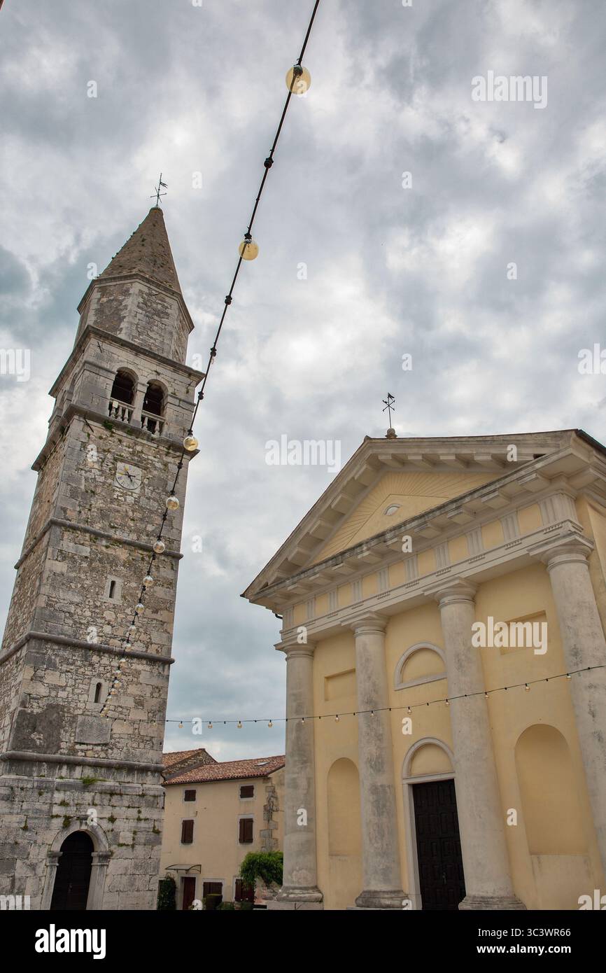 Medieval stone bell tower stands beside neoclassical Church of the Sts ...