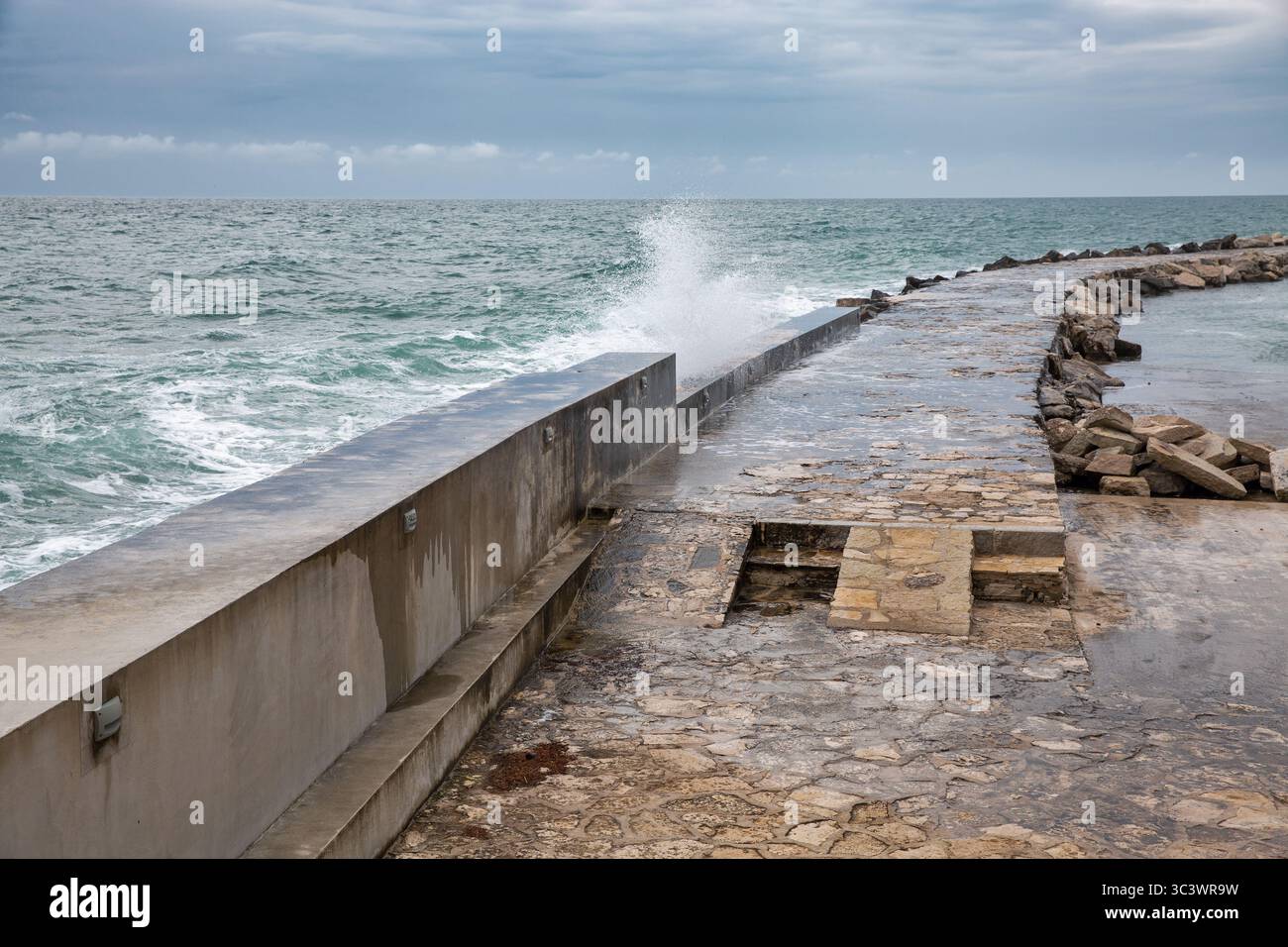 Dramatic sea waves splashing against stone breakwater and concrete wall ...