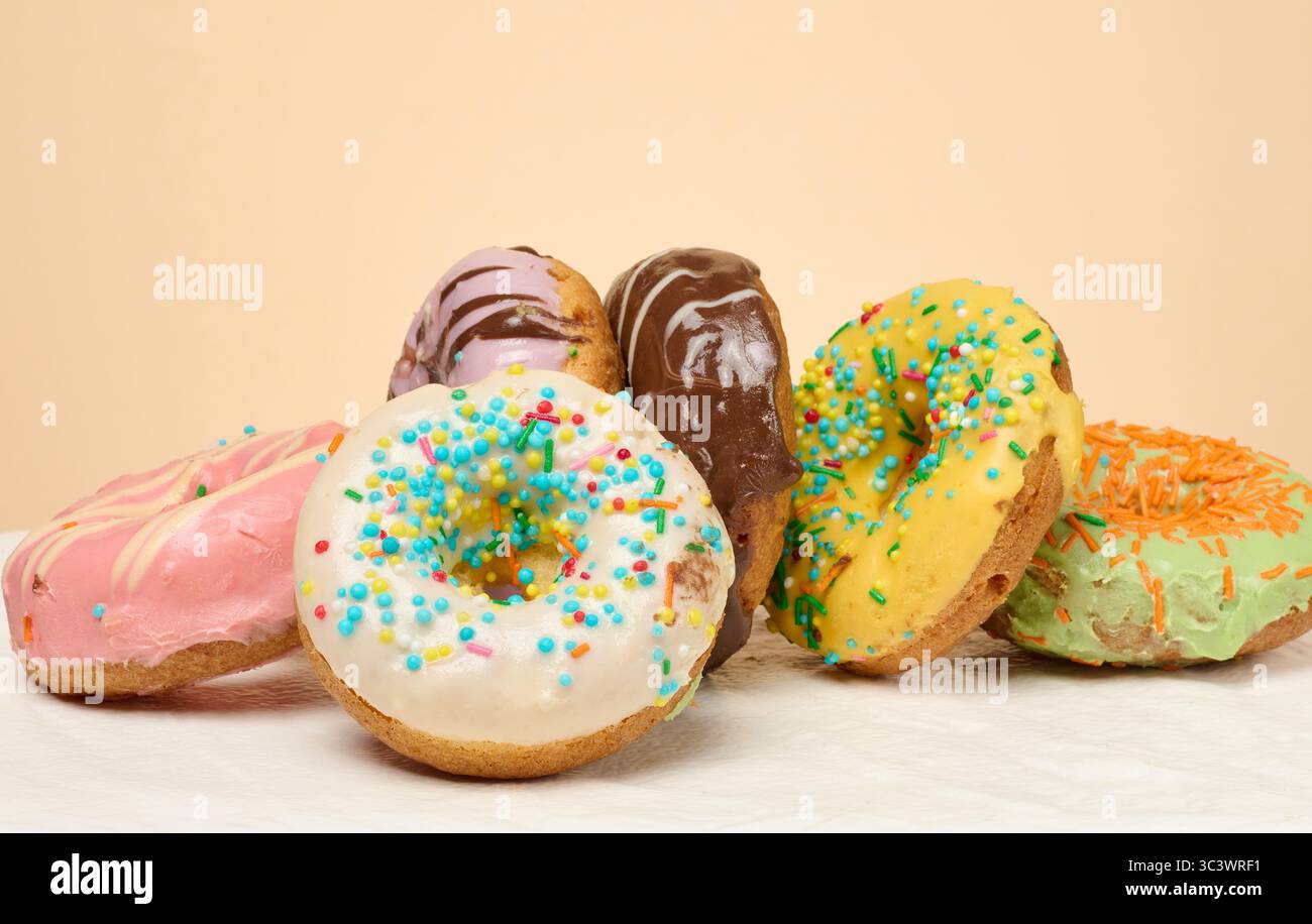 Stack of donuts with different toppings and glazes, beige background ...