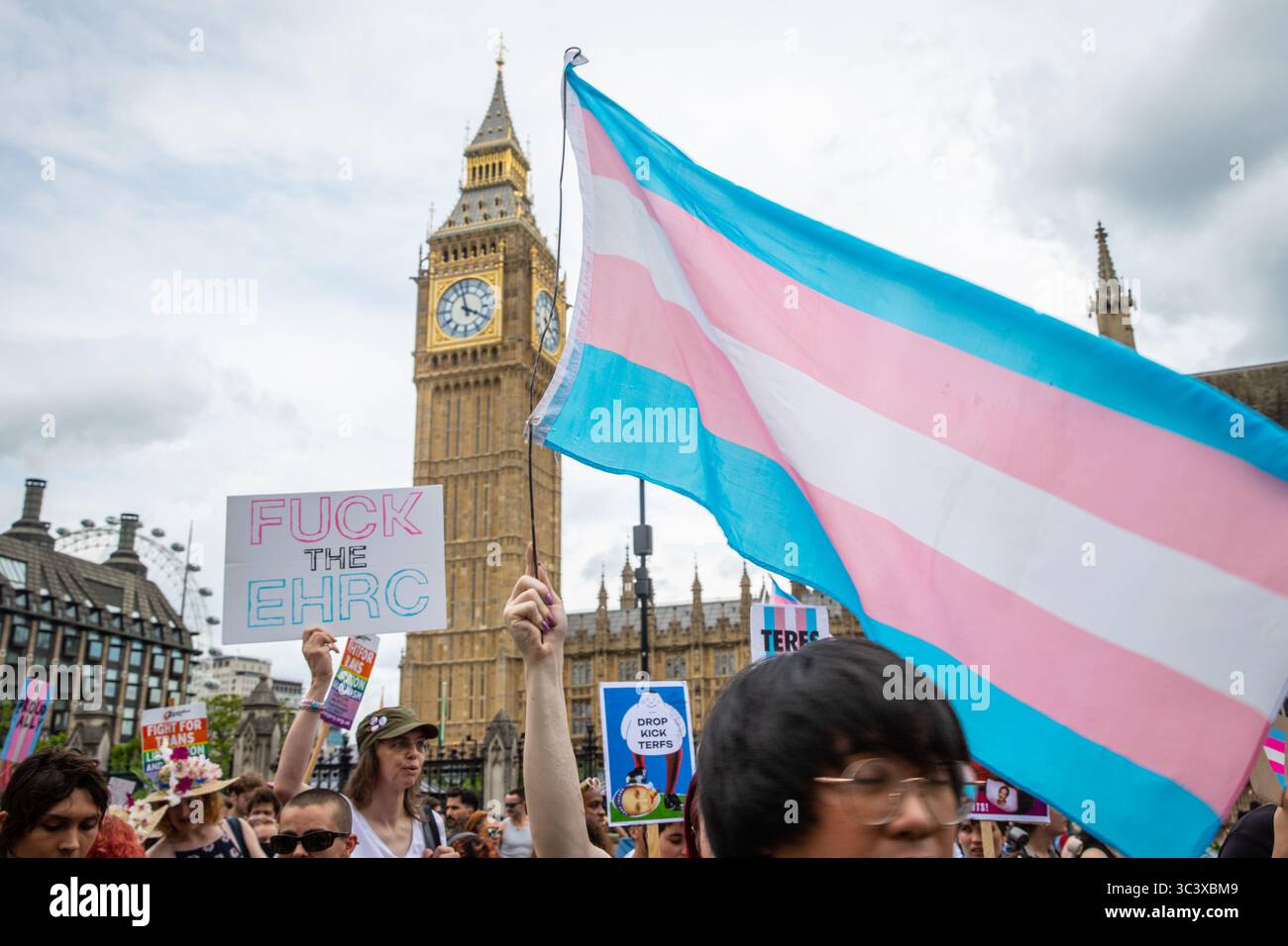 Trans flag and placard against the EHRC in front of the Palace of ...