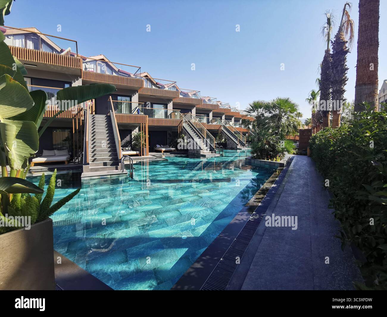 Luxury modern beach hotel with swimming pool. Sunbed on sundeck for ...