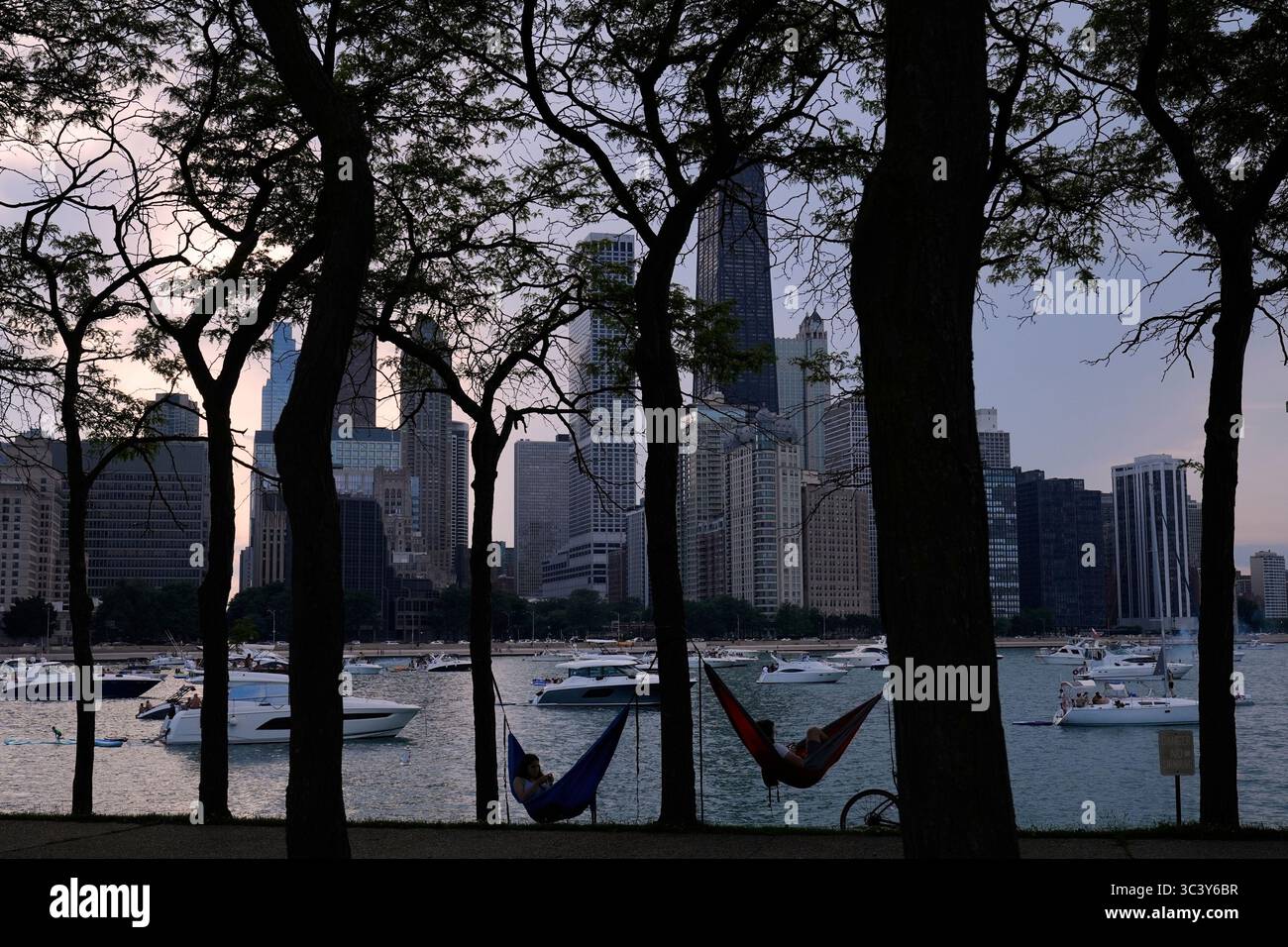 A couple relax on hammocks along the shore of Lake Michigan as boaters ...