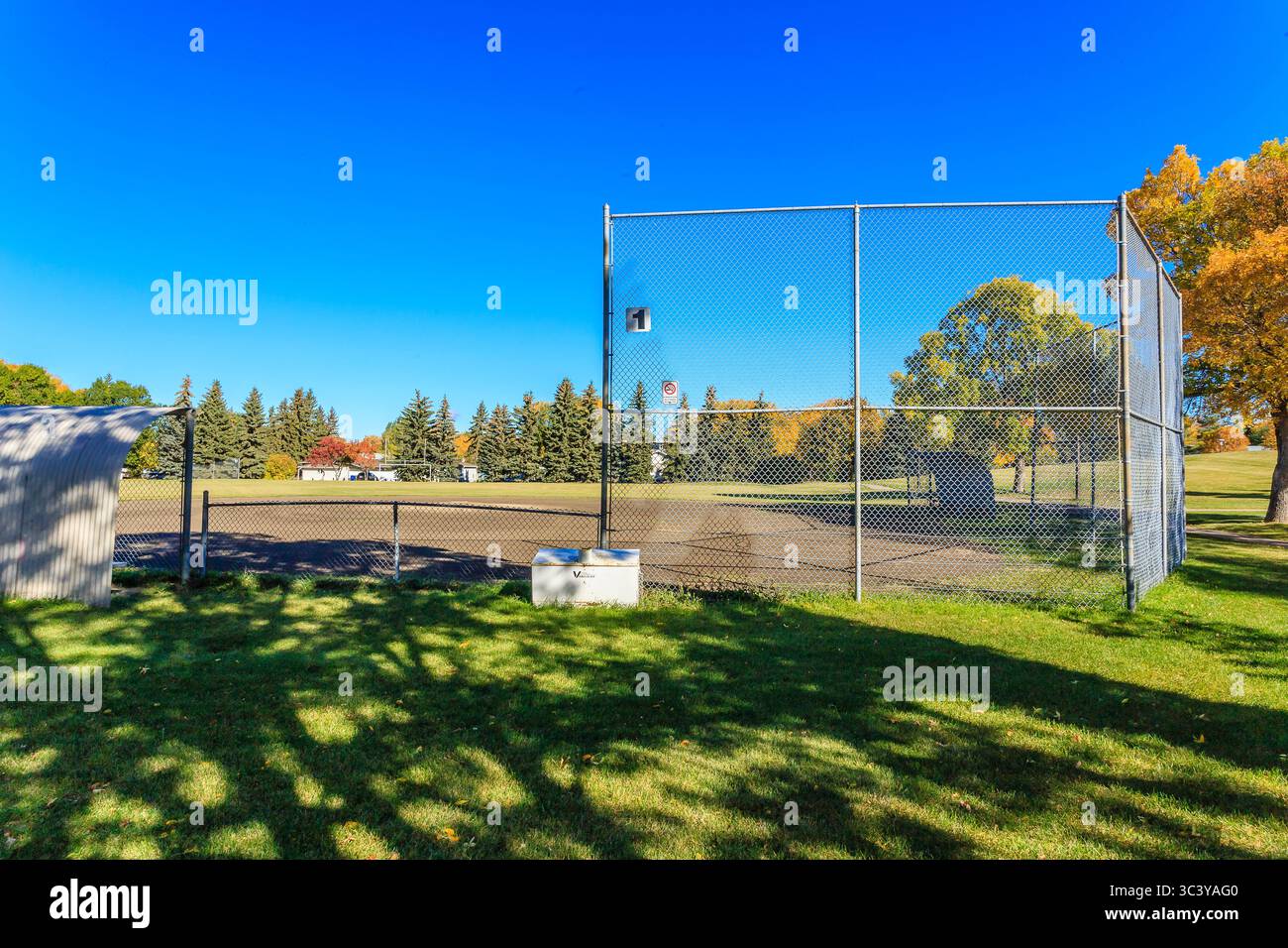 Fenced in area with a baseball diamond and a small shed. The sky is ...