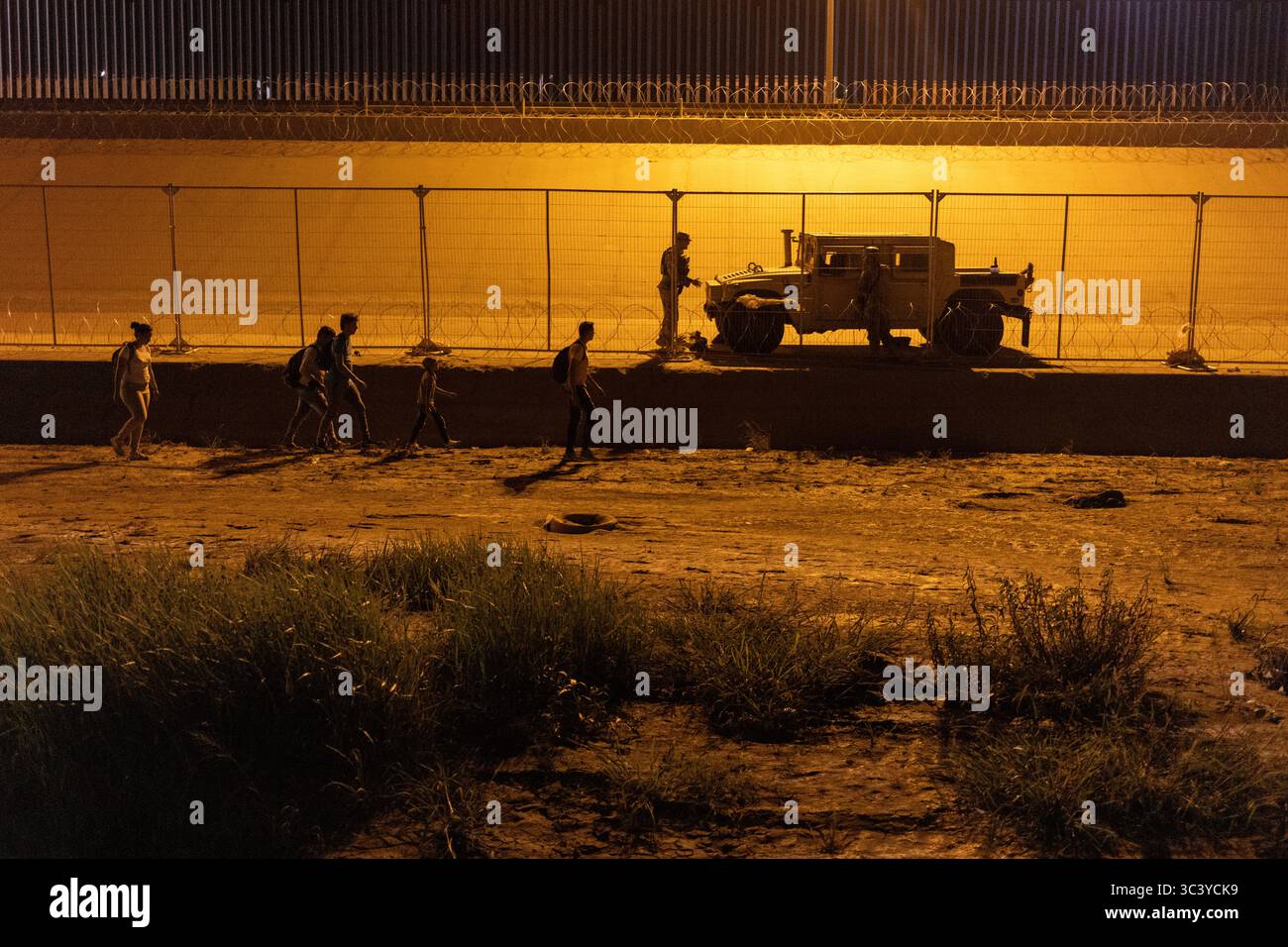 People navigate a brightly-lit border near Ciudad Juarez under military ...