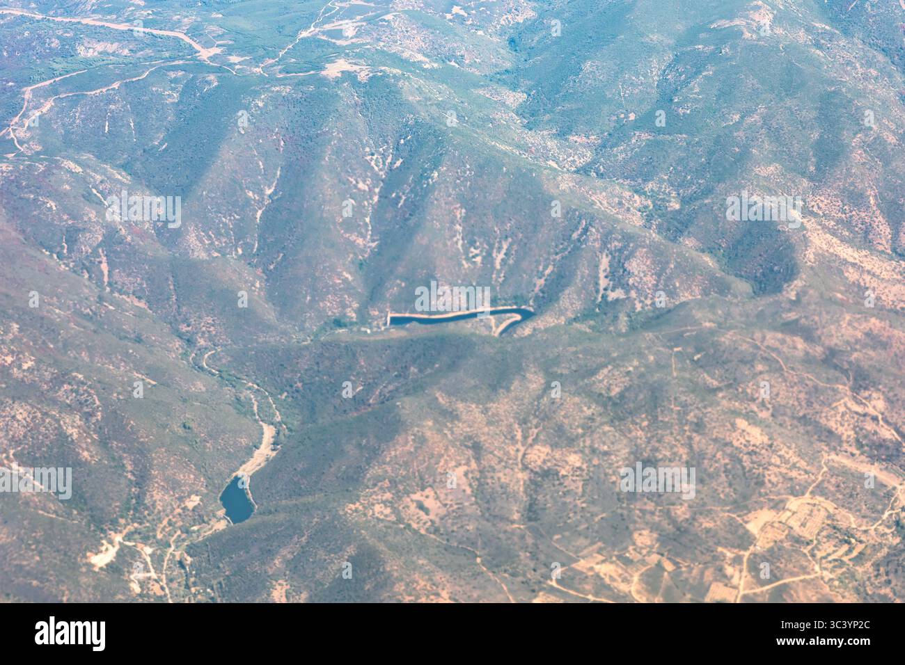 Aerial perspective of a dammed reservoir, showcasing valley contours ...