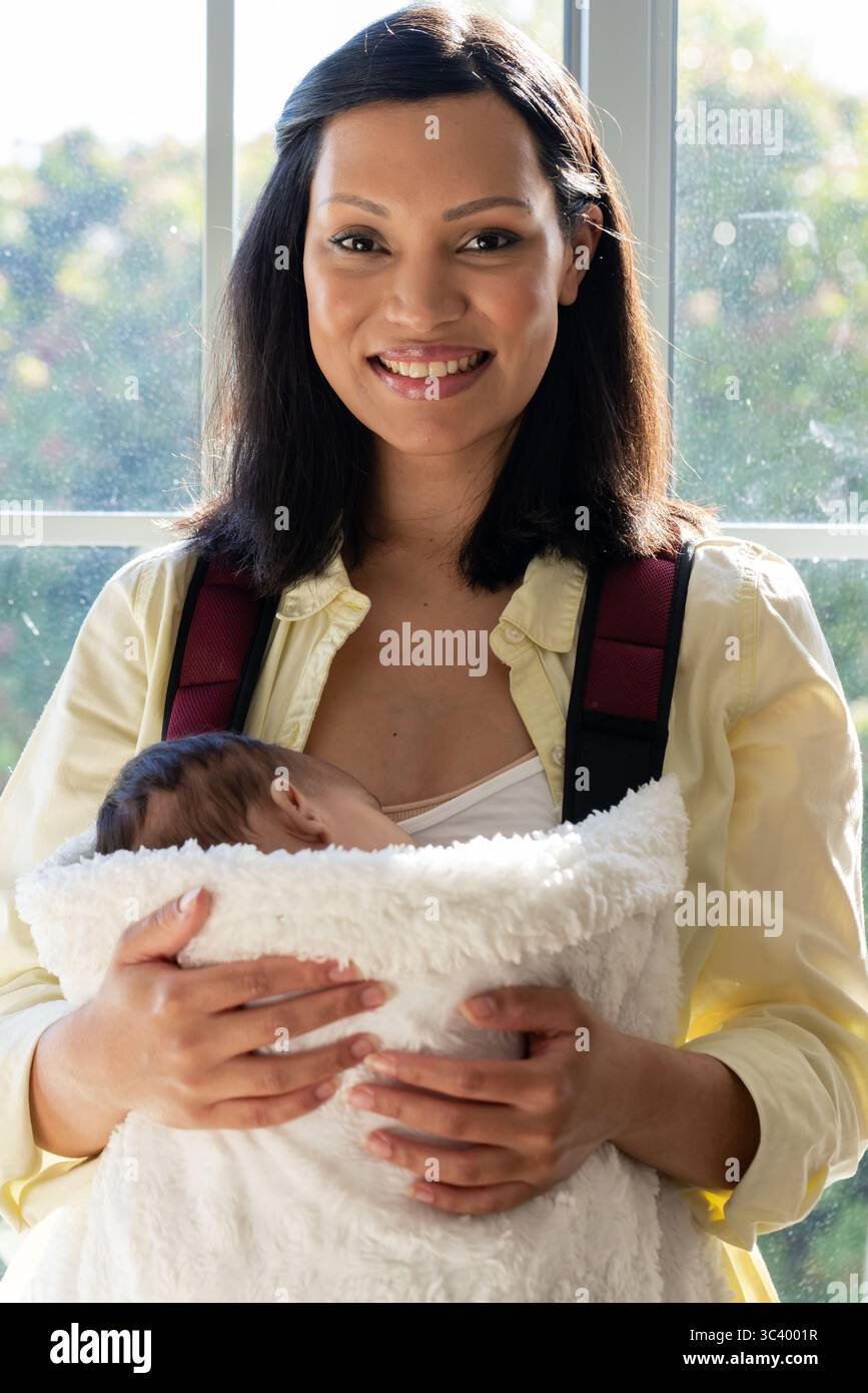 Asian mother in 30s holding newborn in plush blanket using front ...
