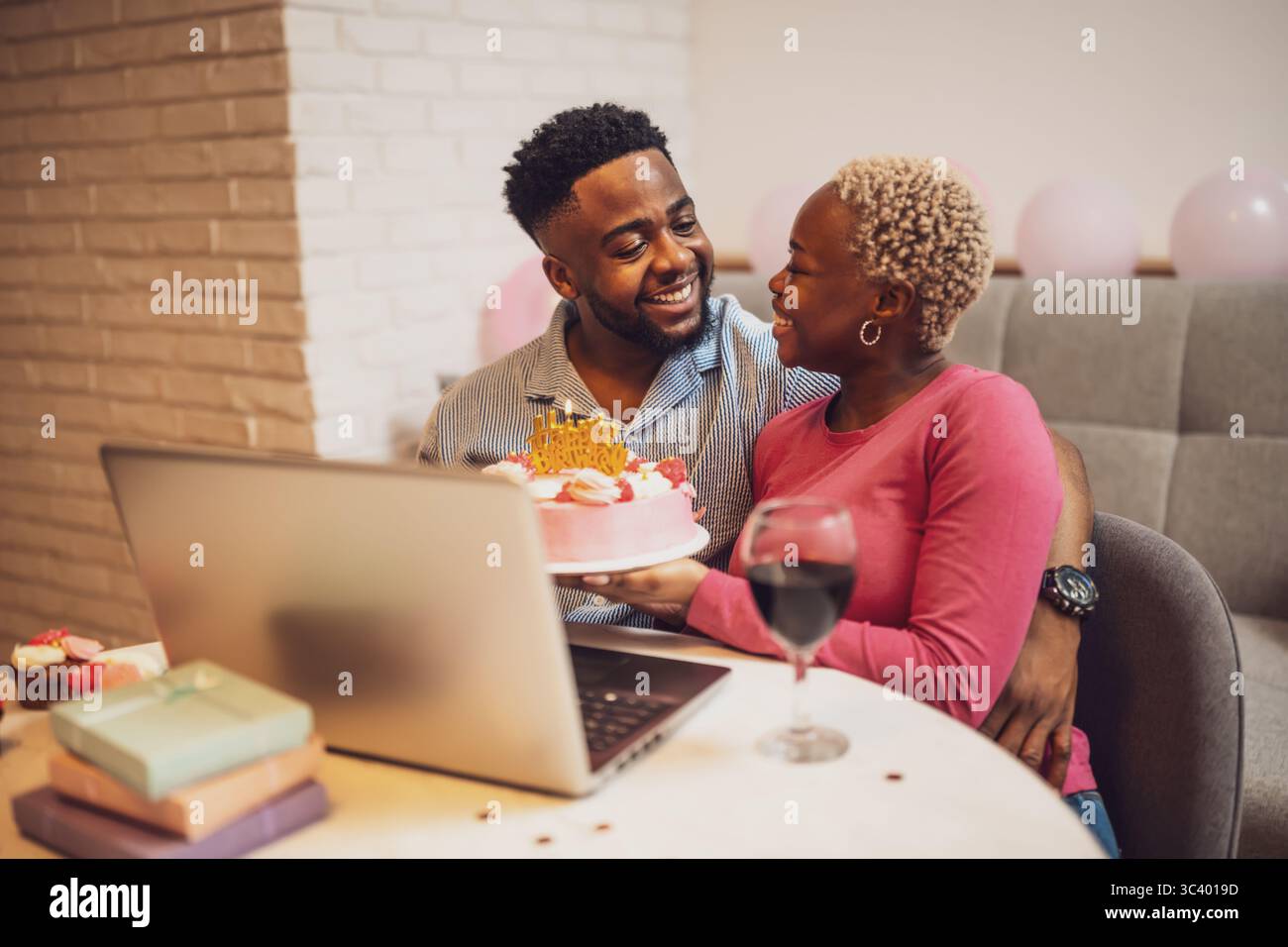 Happy young couple celebrating woman's birthday at home. They are ...
