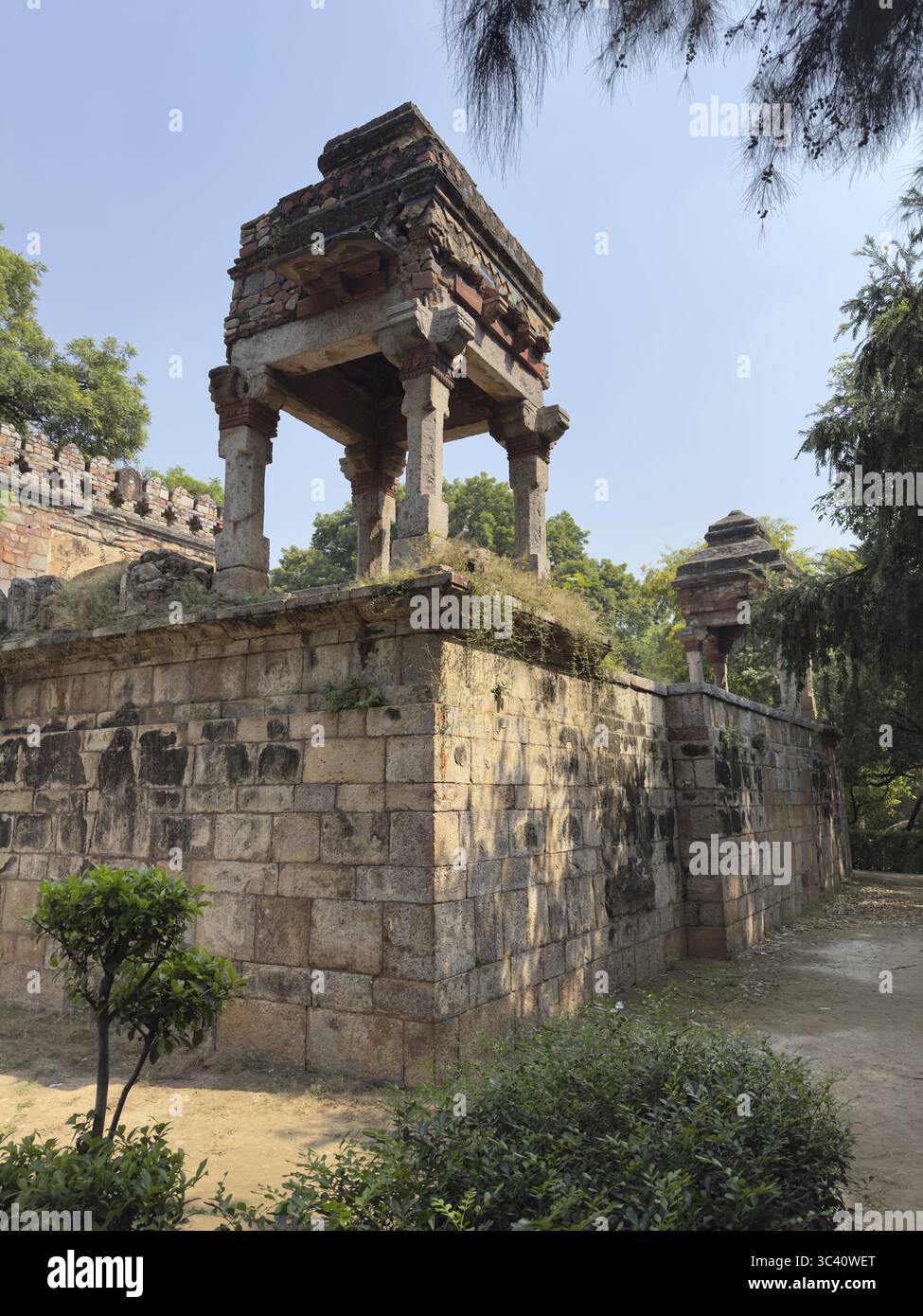 Old sandstone ruins with columns on overgrown grounds under a sunny sky ...