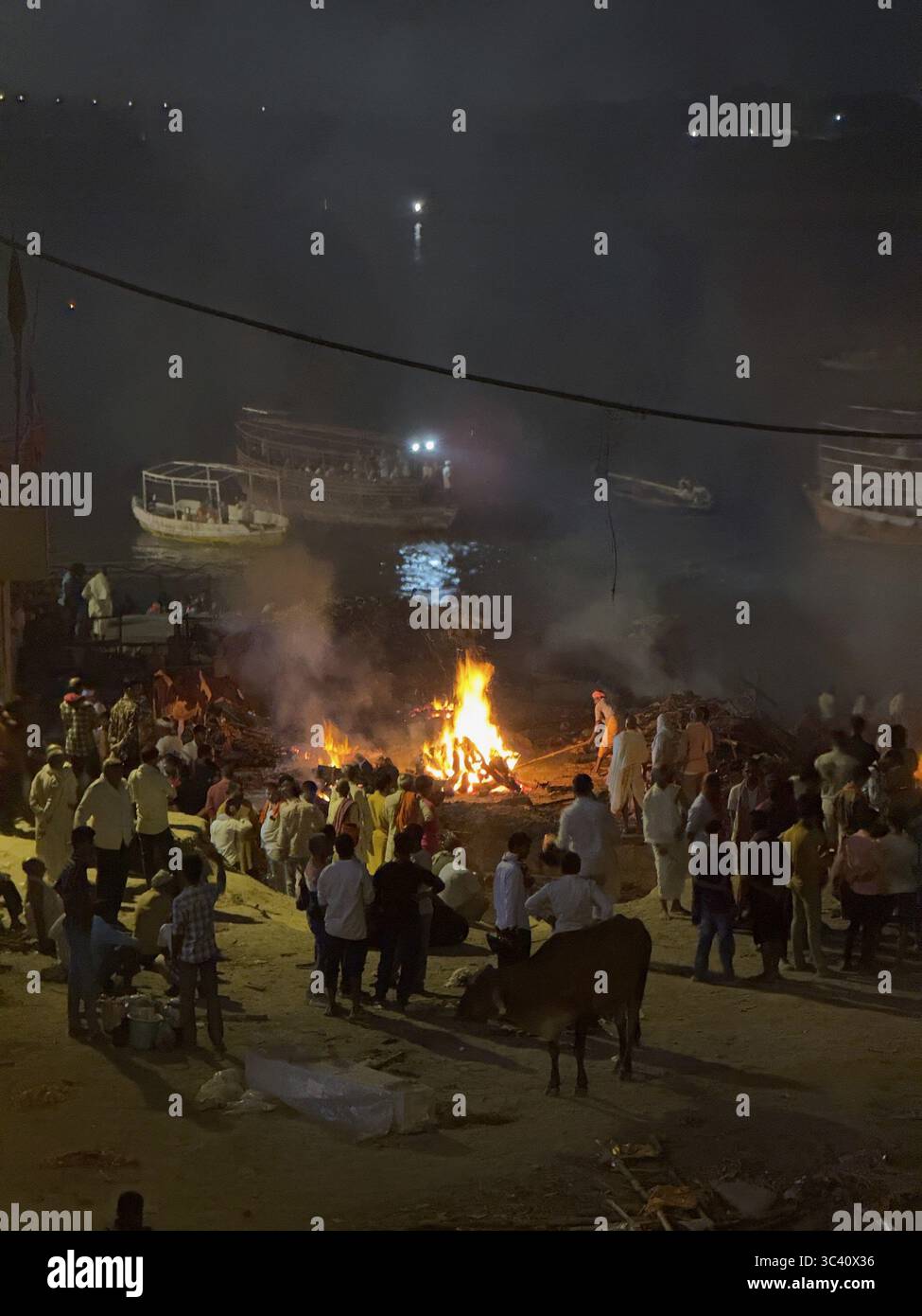 Night cremation on the river bank with burning fire and a large number ...
