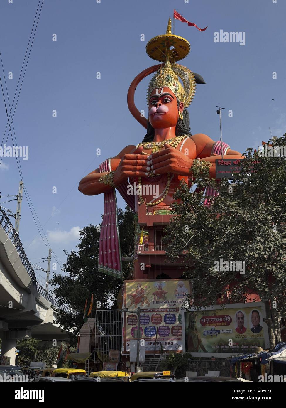 Large Hanuman statue in front of a building along a road with passing ...