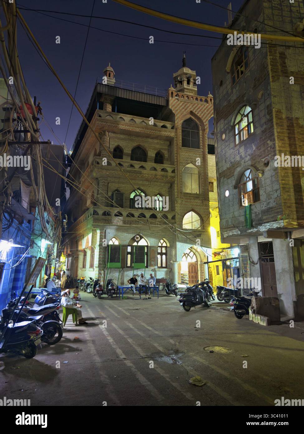 Night view of a busy street with old buildings and motorbikes ...