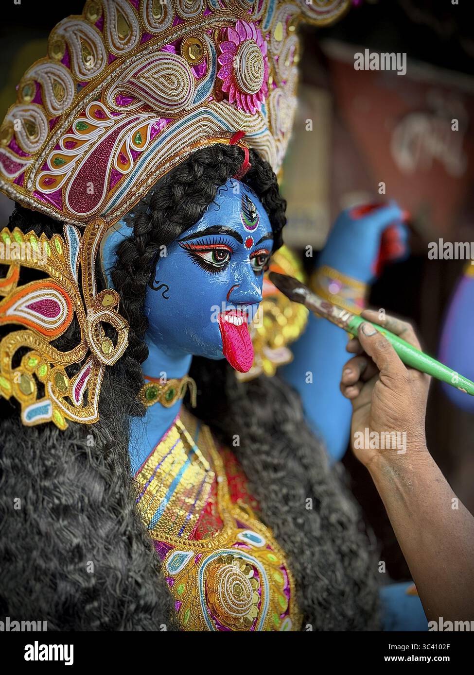 Close-up of an artist painting the face of a Kali statue, richness of ...