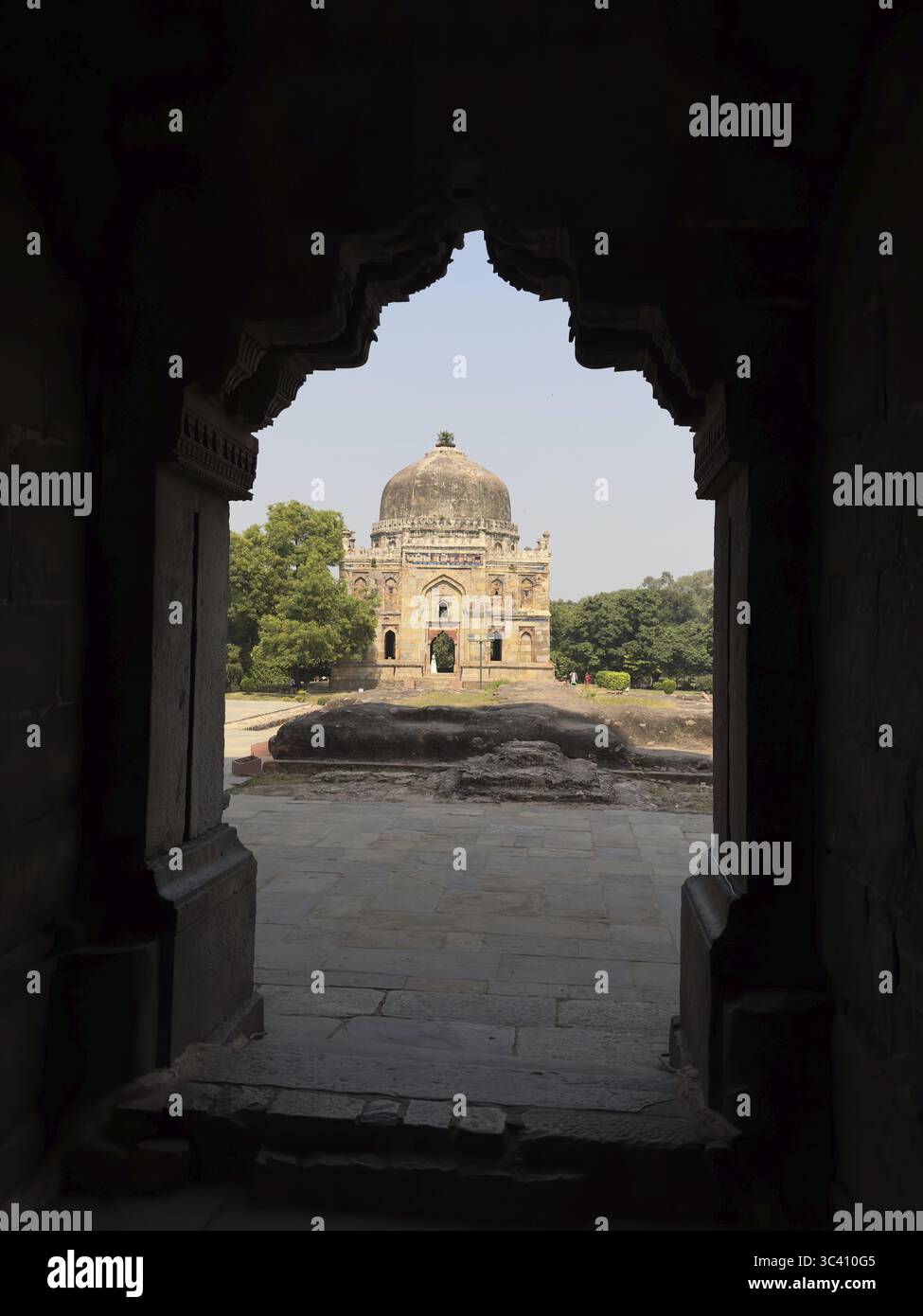 View through a stone arch of an ancient tomb surrounded by trees and ...