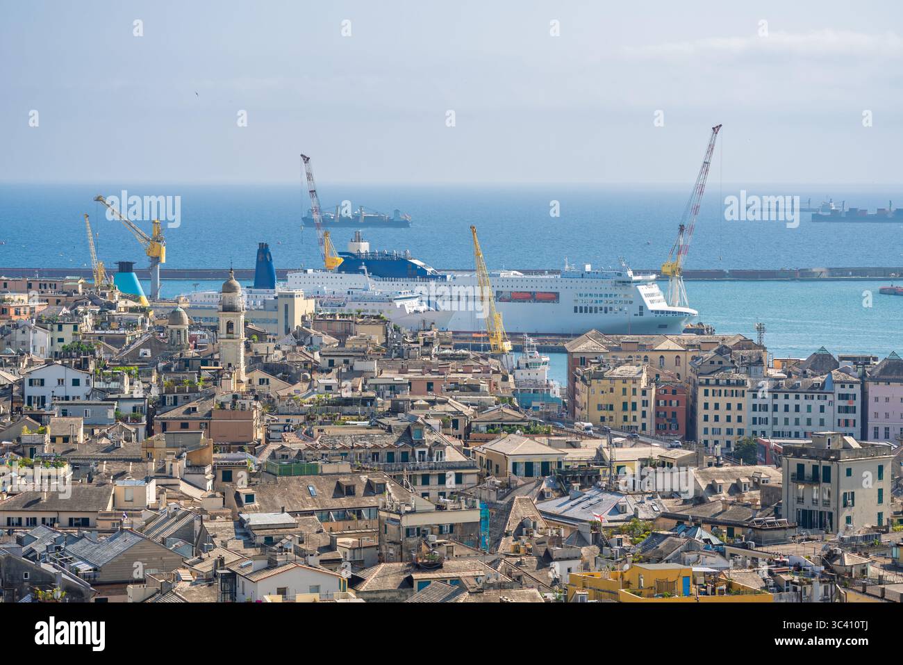 Ferries dock in the Port of Genoa behind a dense skyline of slate ...