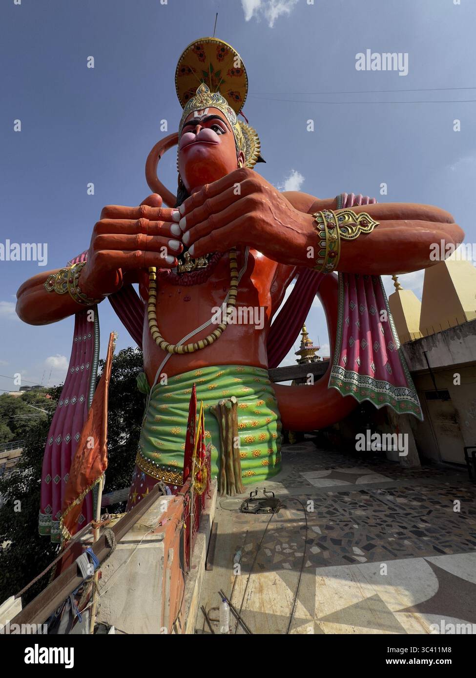 Large Hanuman statue in a temple with vibrant colours under a clear sky ...