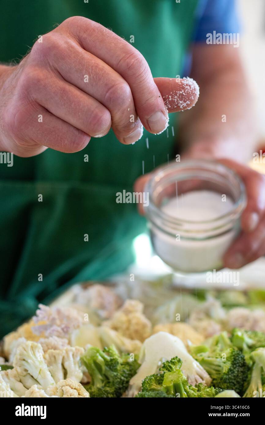 Sprinkling kosher salt over heirloom cauliflower and broccoli Stock ...