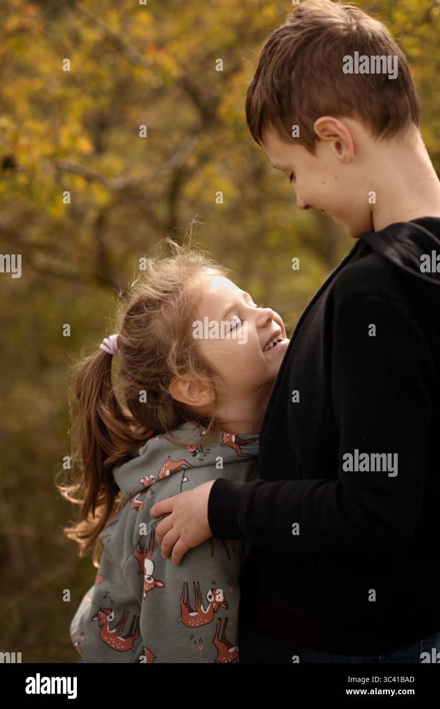 A portrait of a brother and sister sharing a tender hug and smiles ...